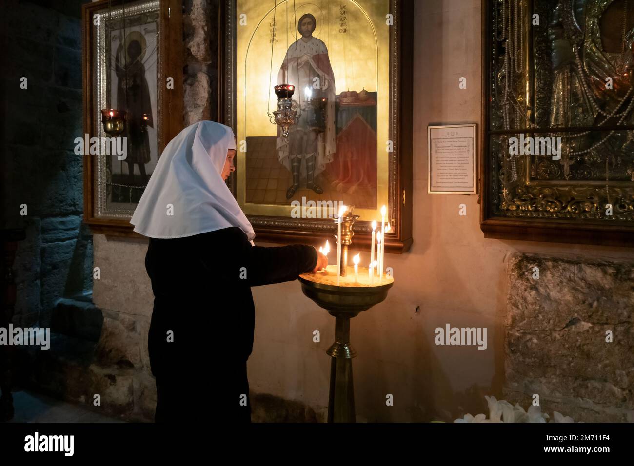 An Eastern Orthodox nun lights candles inside the Russian Church of ...