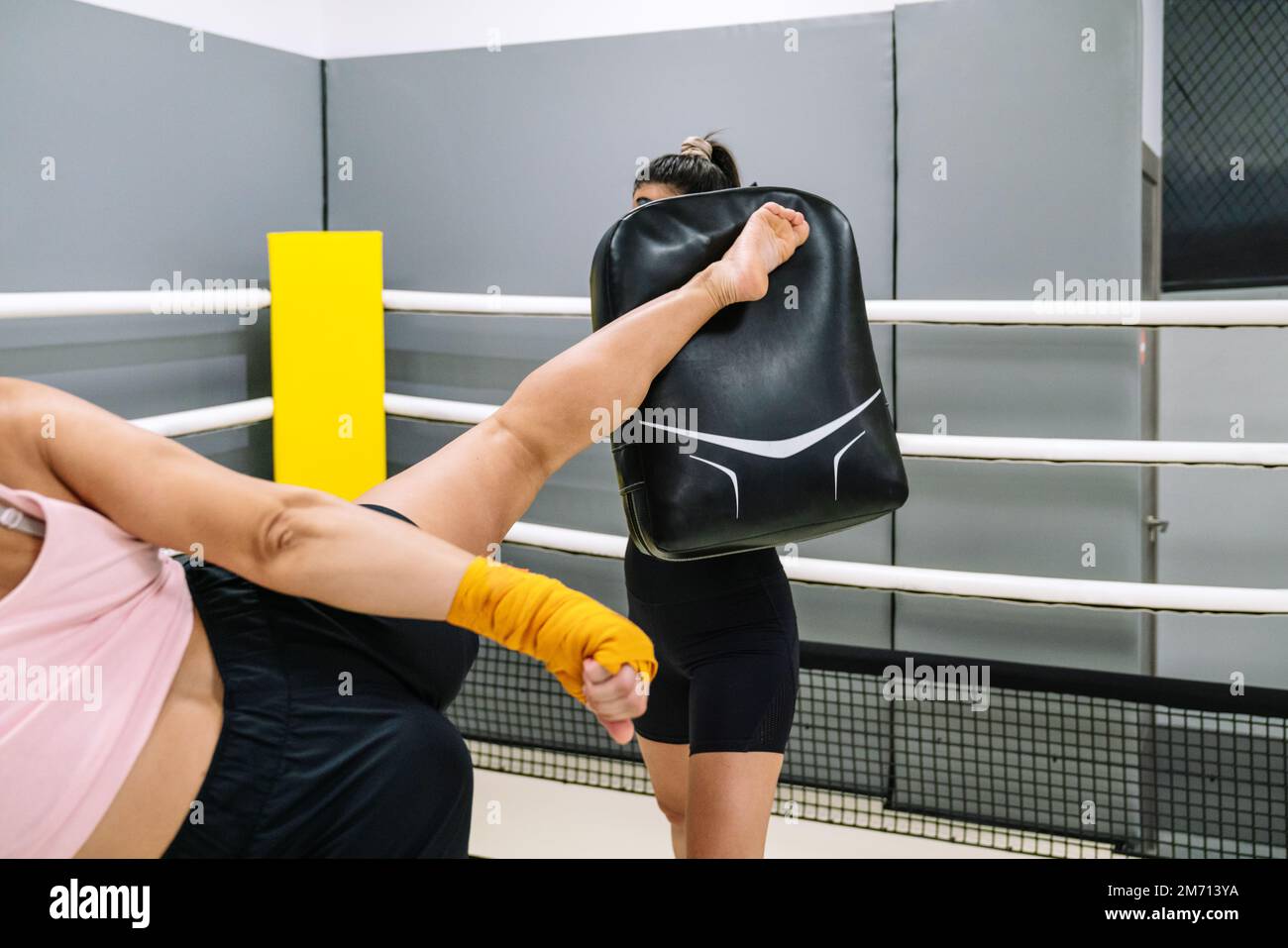 Kickboxer giving a high kick in training with his coach in the ring ...