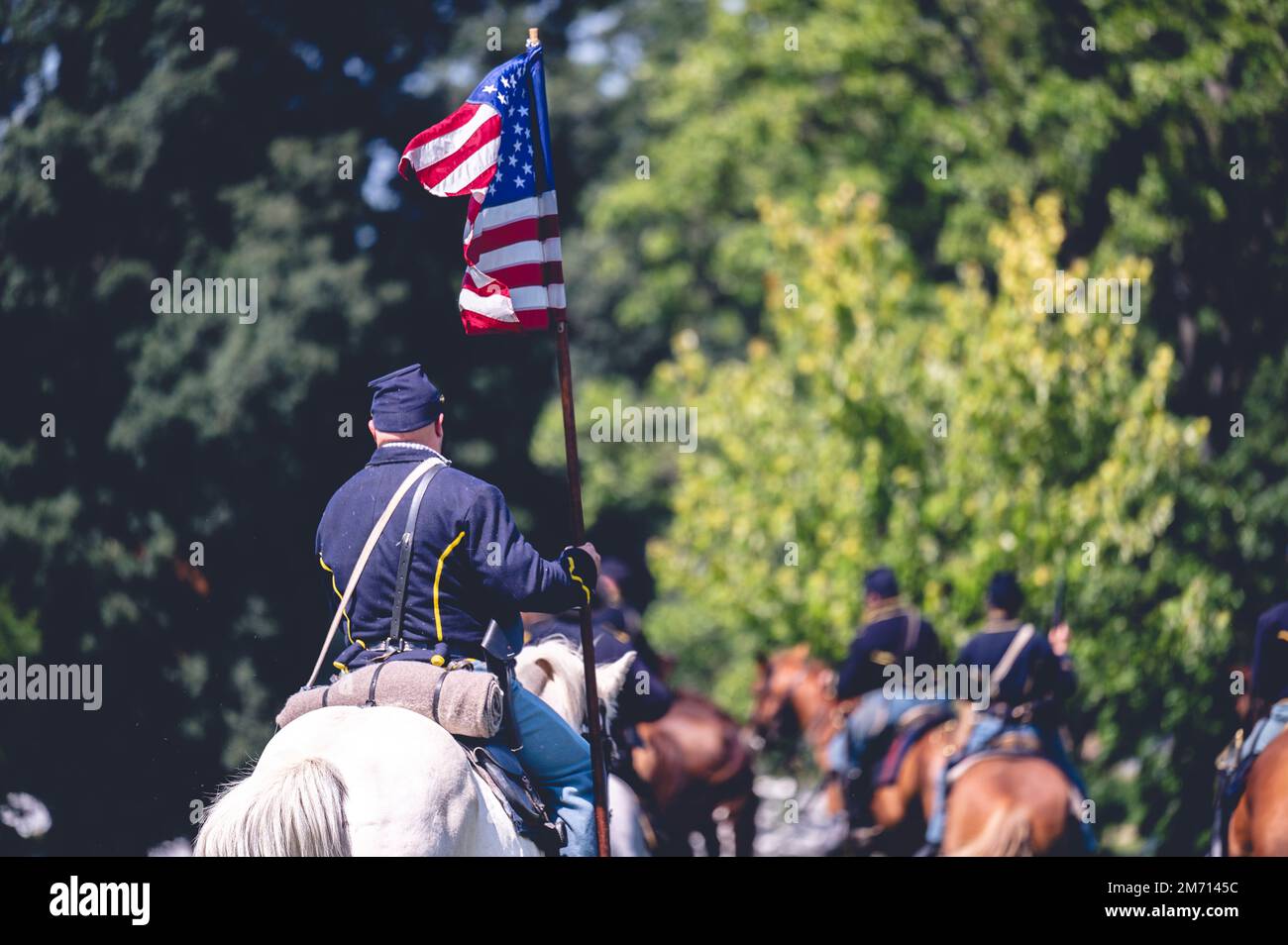 A soldier riding a horse and raises the flag of America during military ...