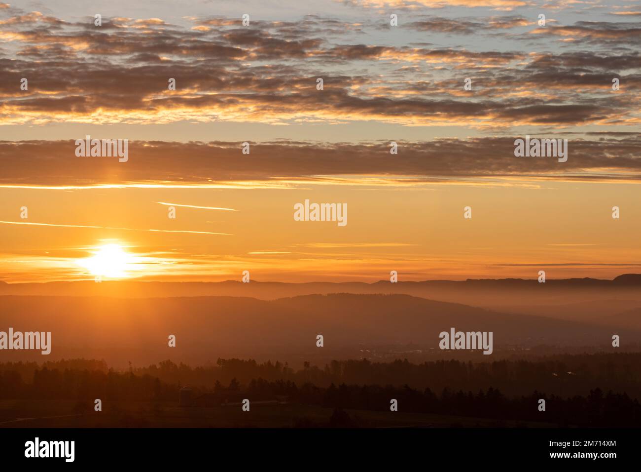 sunrise with sun shining into the camera in germany swabia with hazy ...