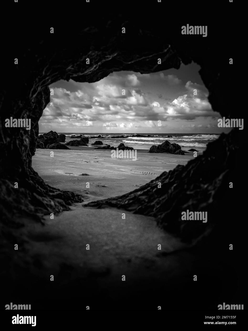 A grayscale vertical shot of sea and beach from inside cave Stock Photo ...