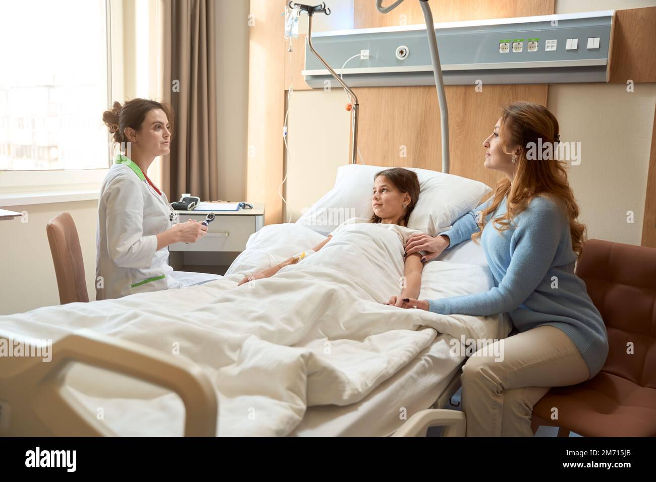 Mom and doctor communicate at the bedside of recovering girl Stock ...