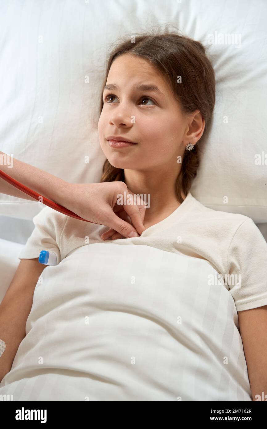 Teenage girl lies on bed with thermometer under her arm Stock Photo - Alamy