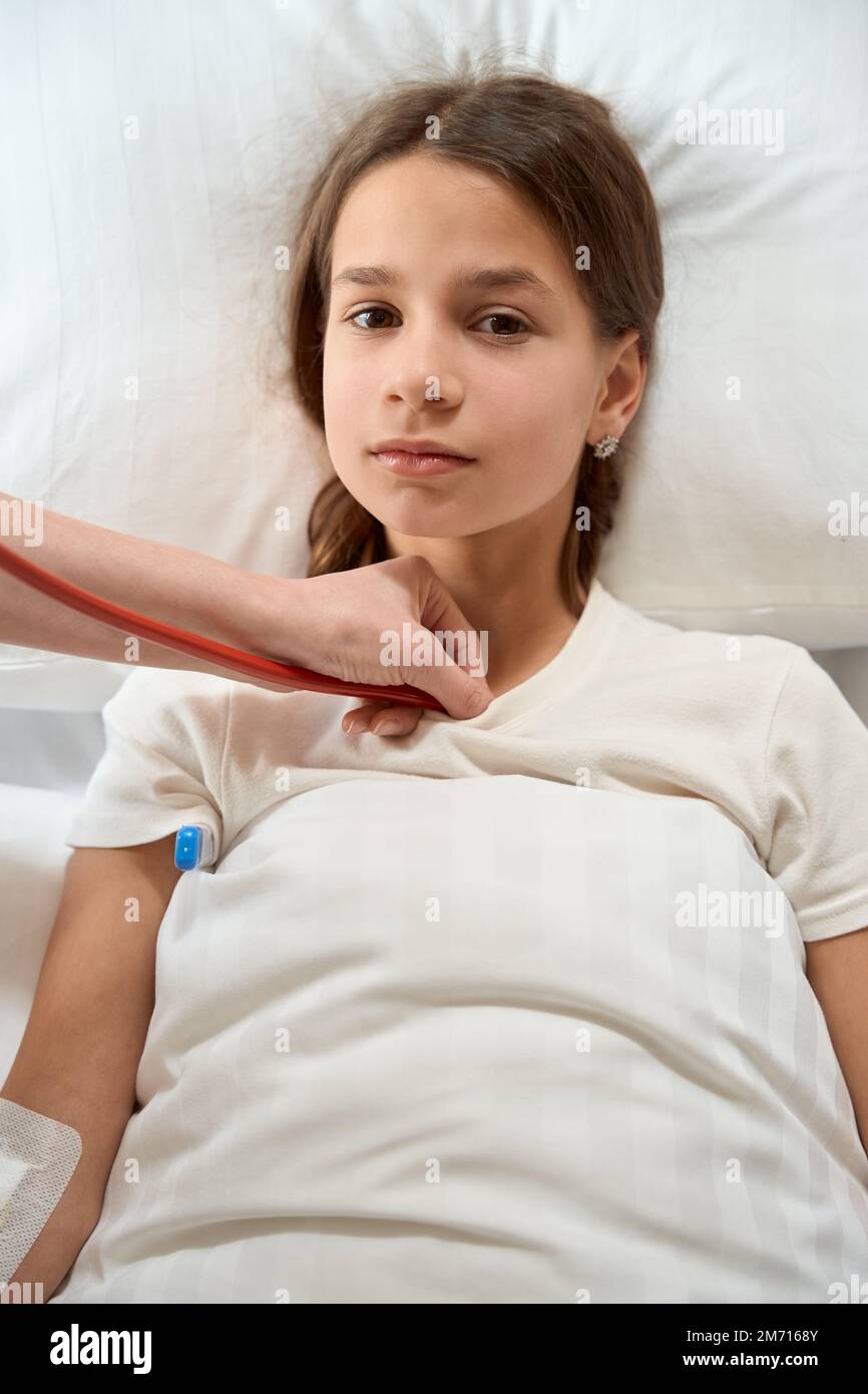 Sad girl lies on bed with thermometer under her arm Stock Photo - Alamy