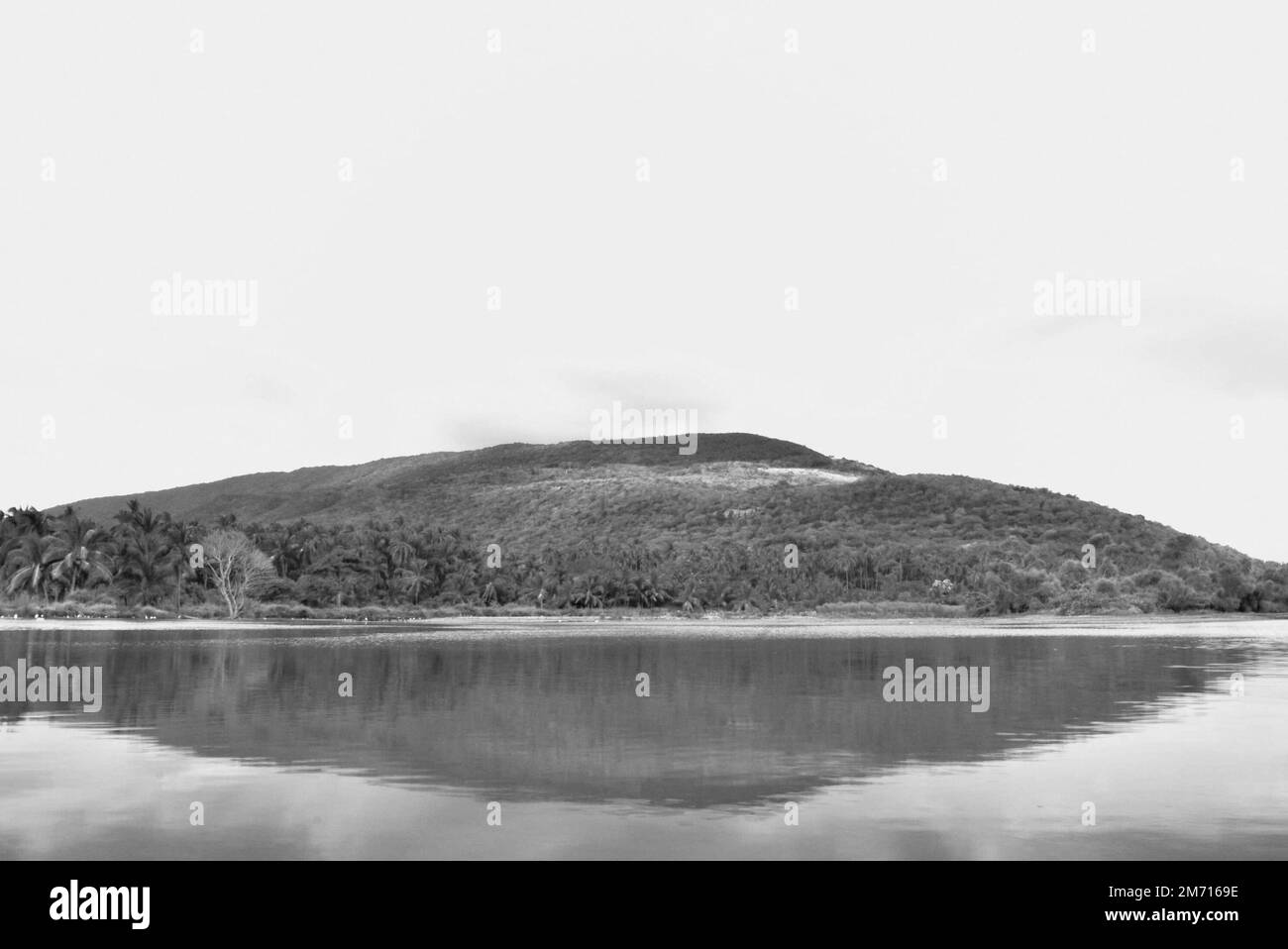 A grayscale of a hill reflected in the calm sea waters in La Ticla ...