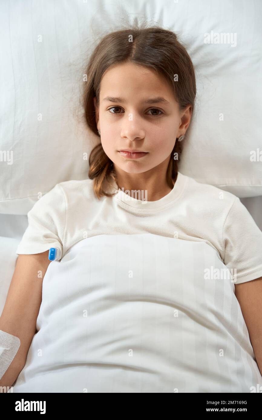 Pretty girl lies on bed with thermometer under her arm Stock Photo - Alamy