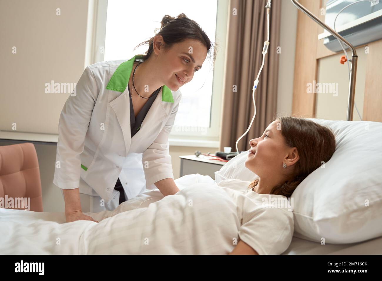 Kind woman doctor bent over the girl Stock Photo - Alamy