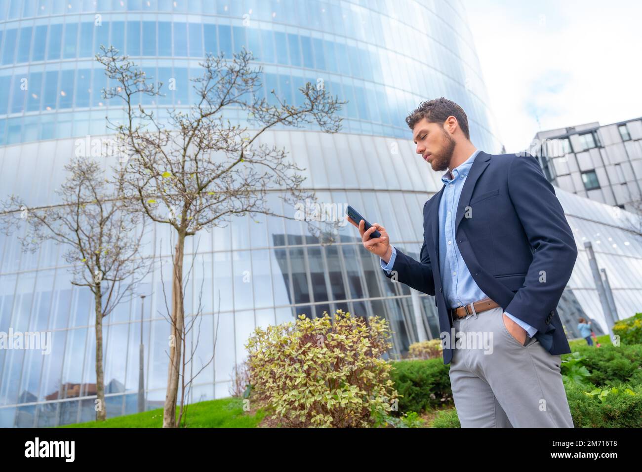 Male businessman or entrepreneur looking at mobile outside the office ...