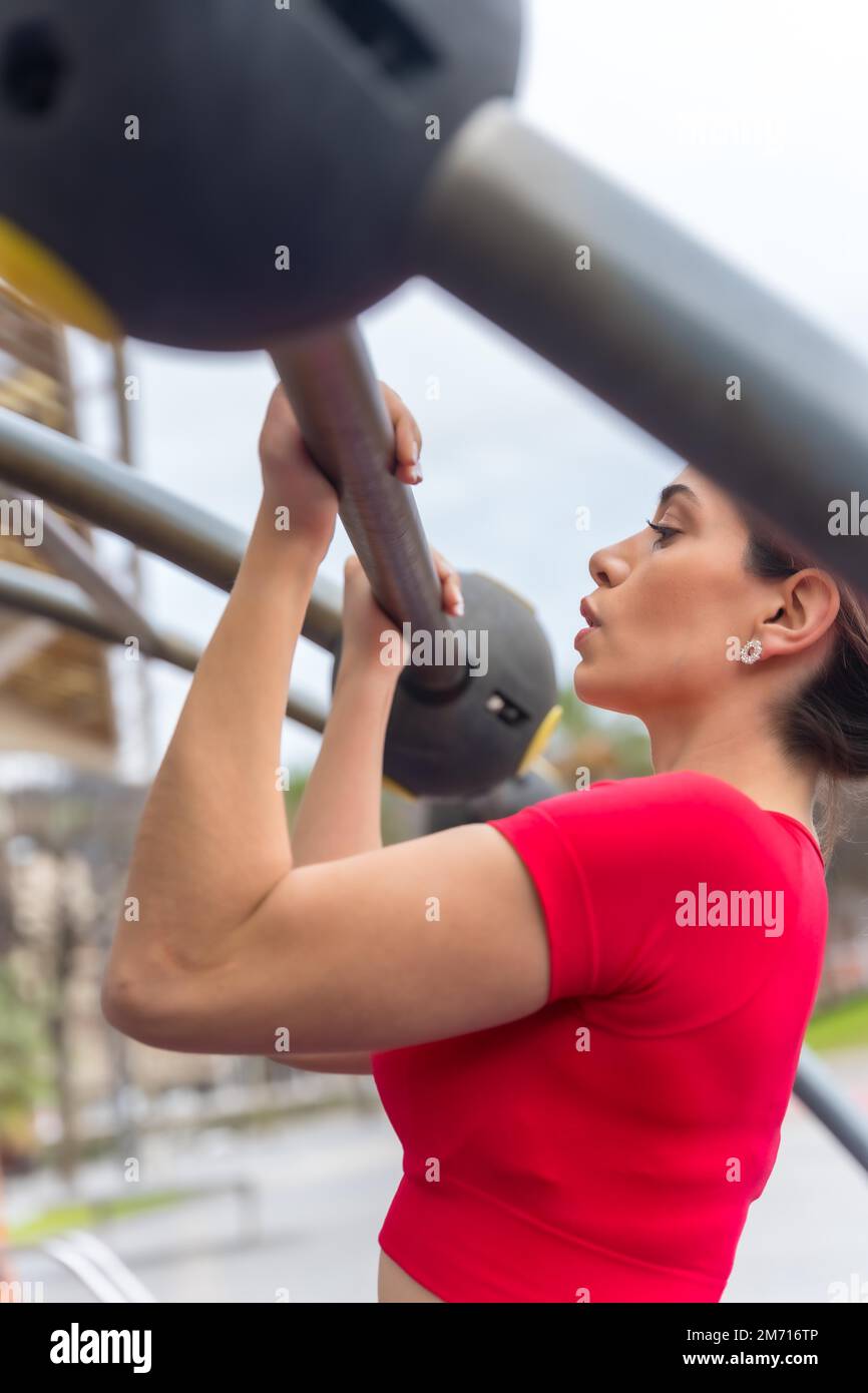 Fit woman in red outfit doing arm exercises on some bars, fitness and ...