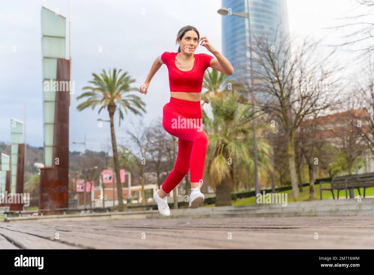 Fit woman in red clothes doing jogging exercises in the city, fitness ...