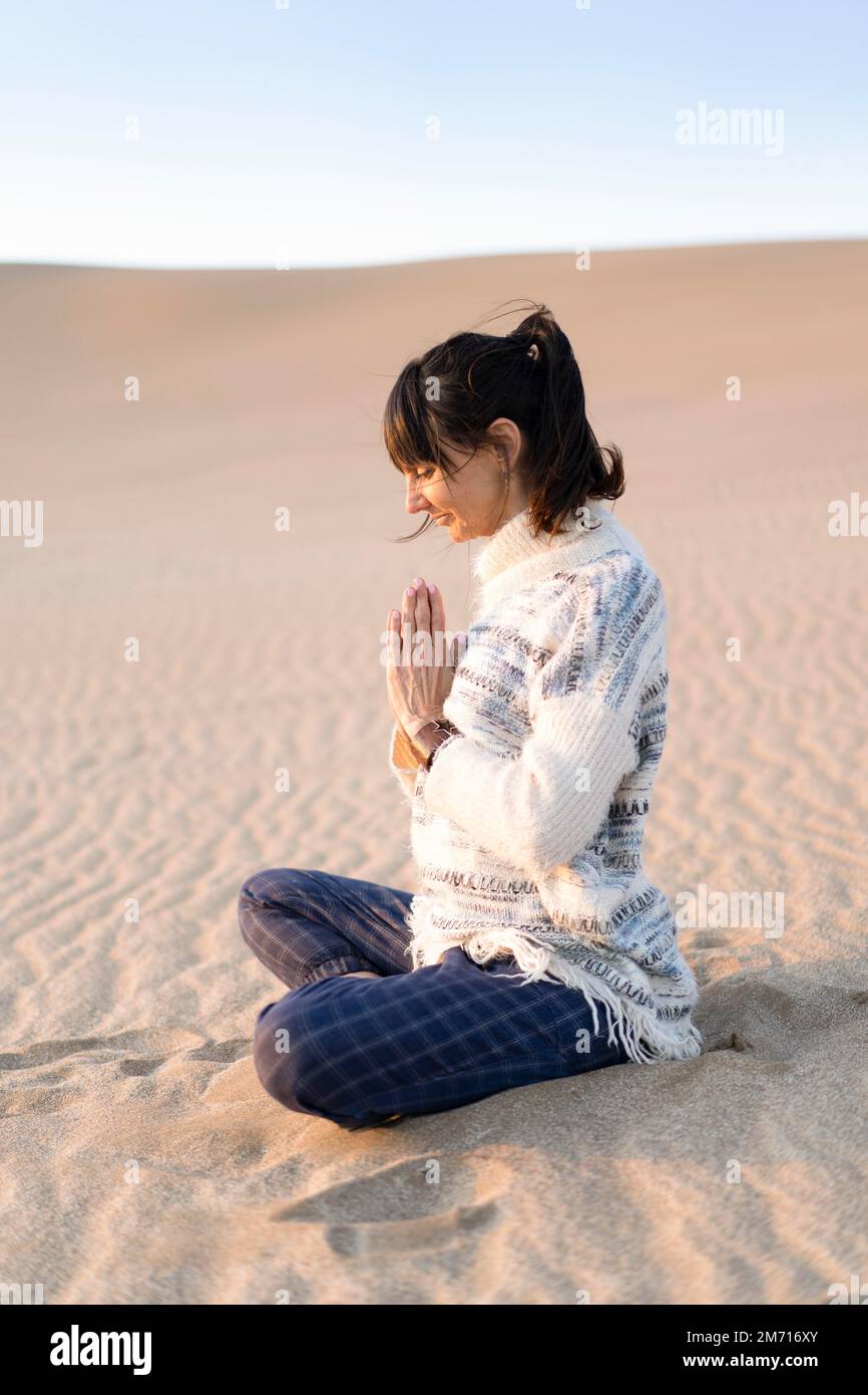 Side view of a woman clasping hands at the beach. Namaste pose Stock ...