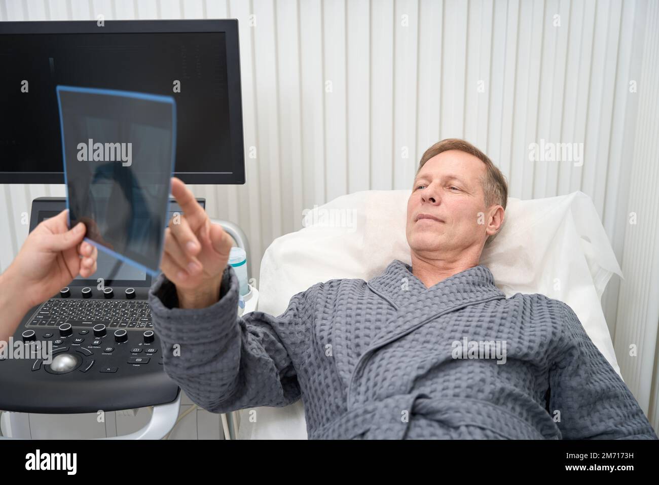Relaxed patient studying an x-ray picture of his knee at clinic Stock ...