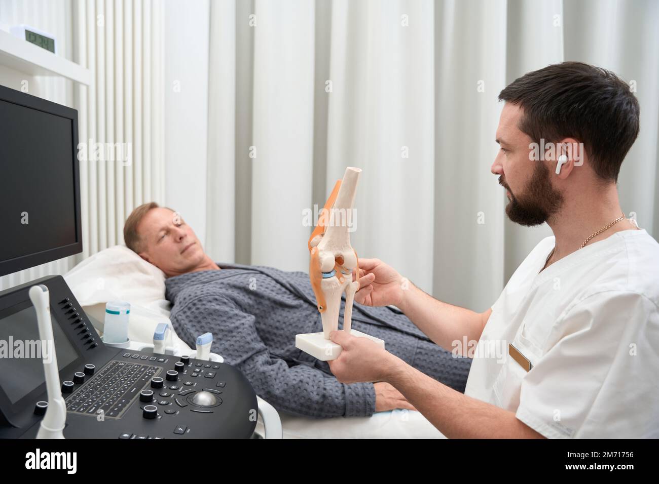 Experienced orthopaedist explaining the anatomy of human knee to his ...