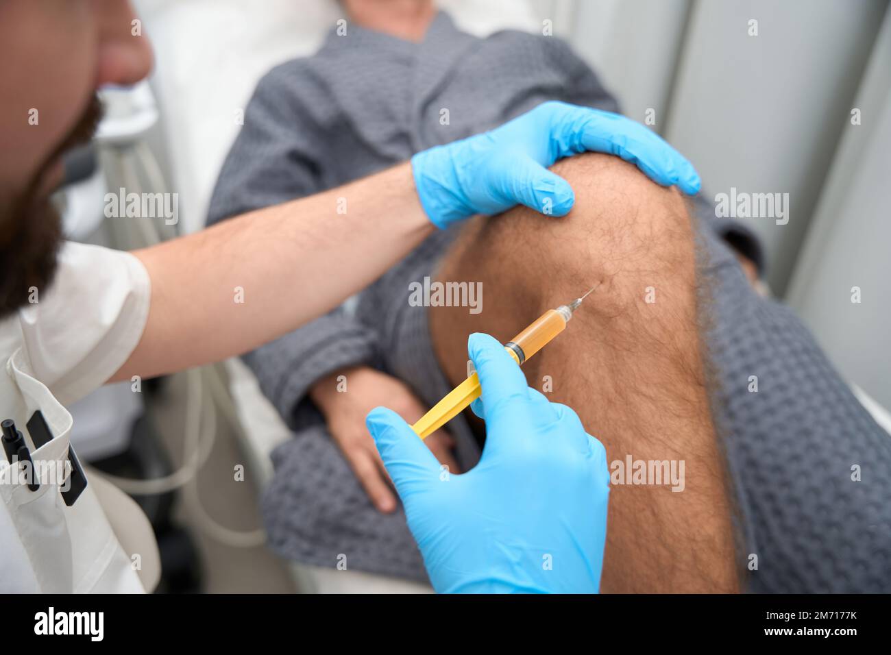 Experienced doctor taking a biopsy sample from man knee Stock Photo - Alamy