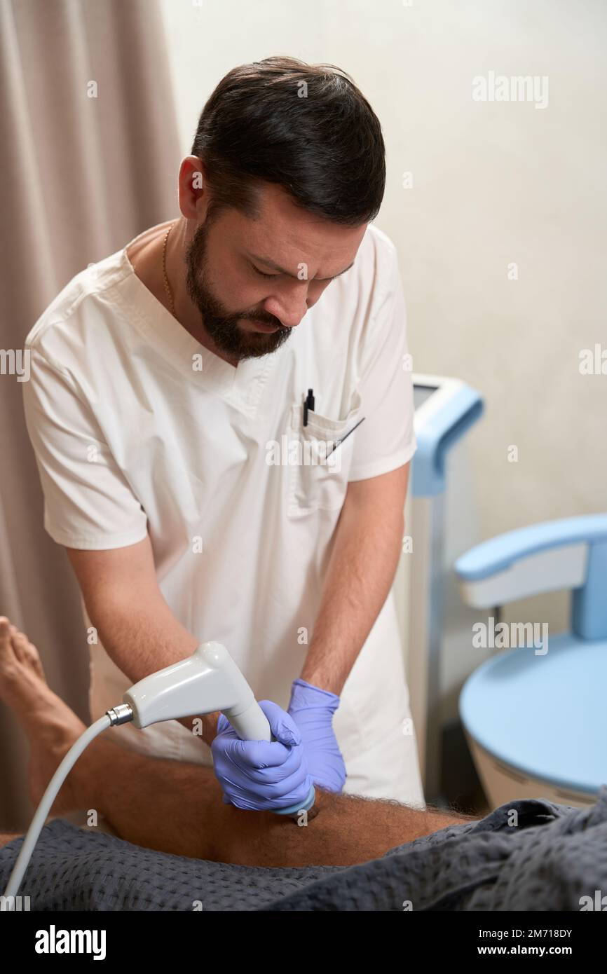 Concentrated medic treating his patient with radiofrequency therapy ...
