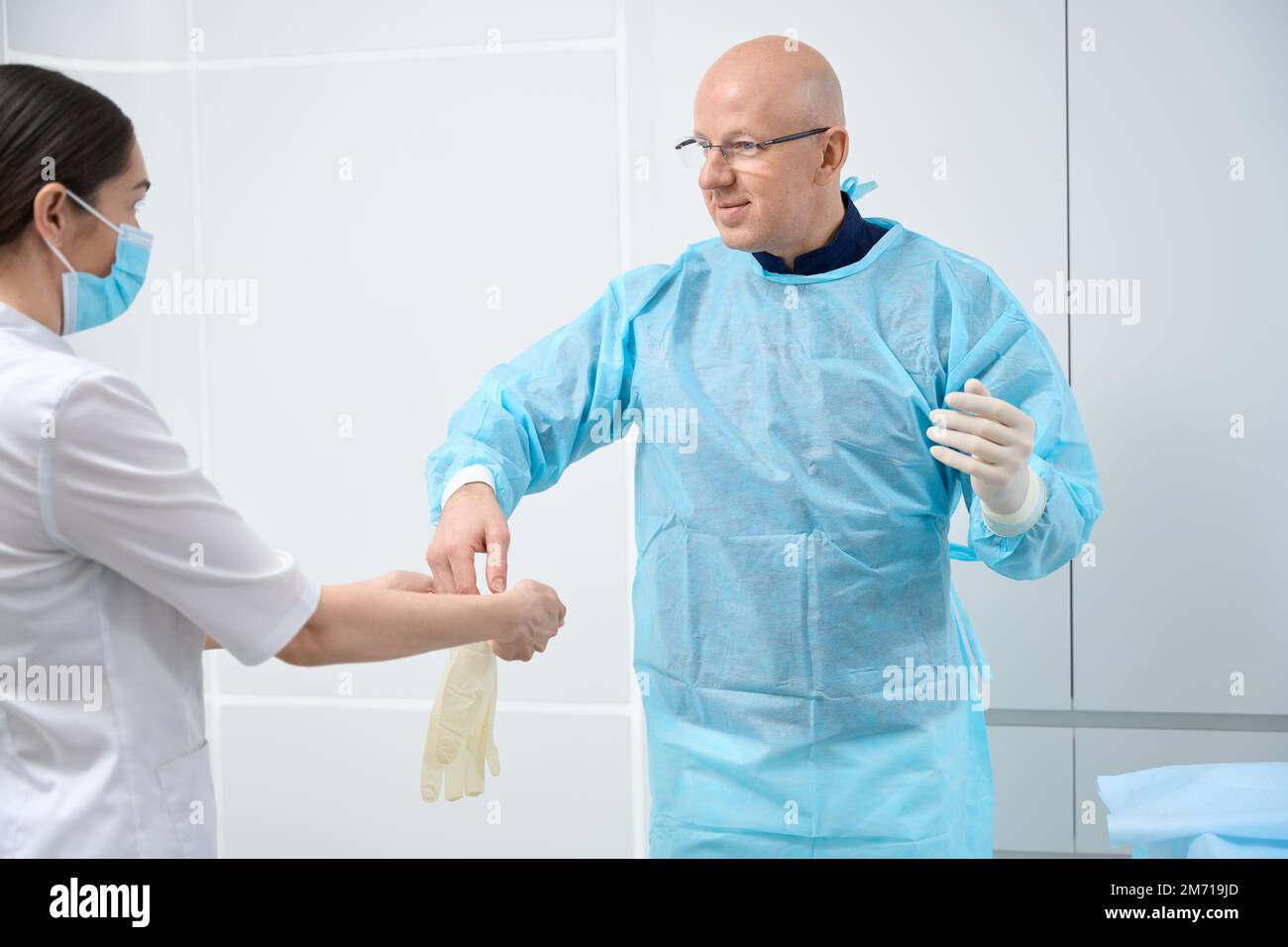 Gladsome doctor having his personal protective equipment put on Stock ... Gladsome doctor having his personal protective equipment put on Stock ...