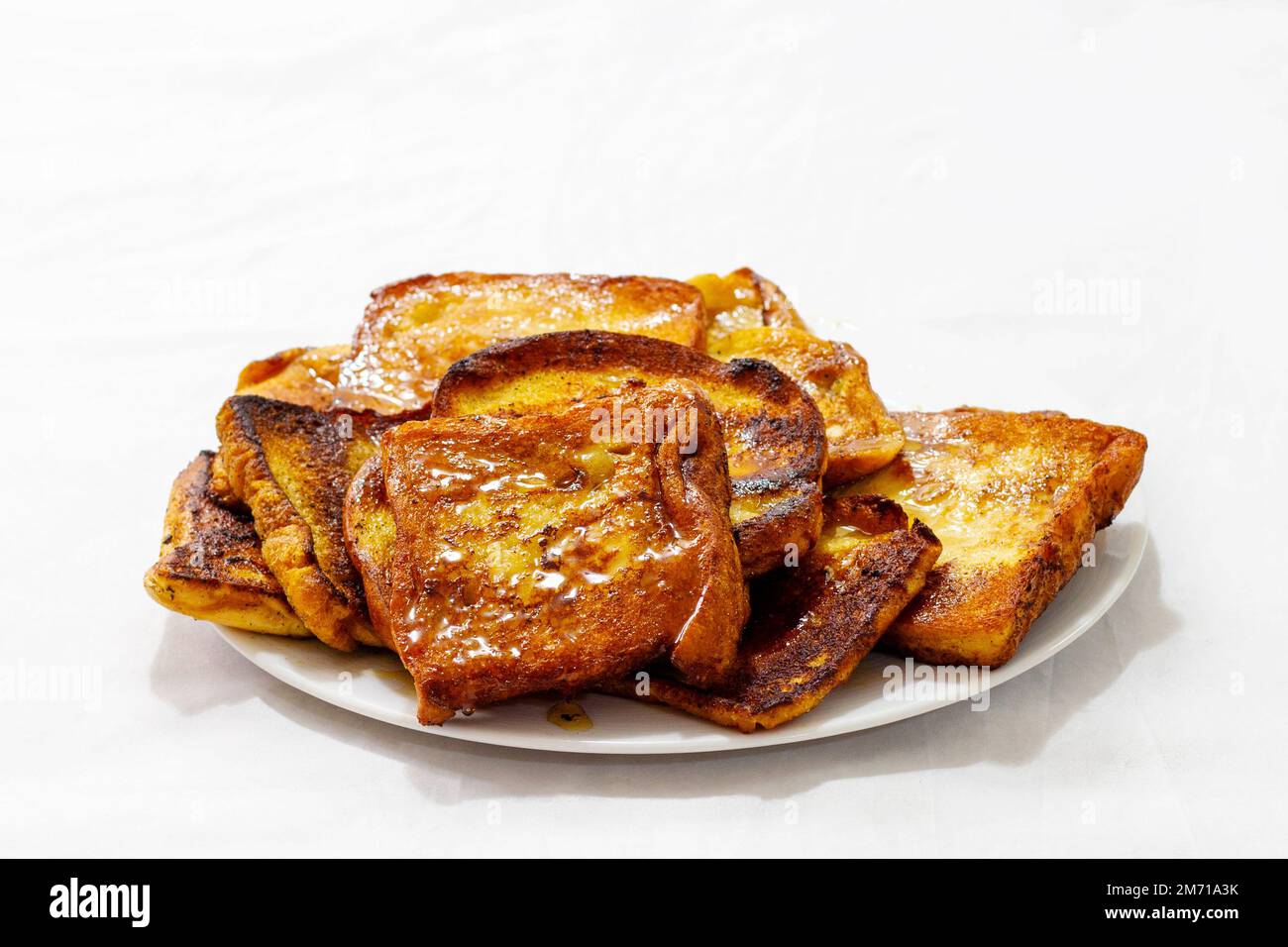 slices of toasted bread in syrup on a white plate on a white background ...