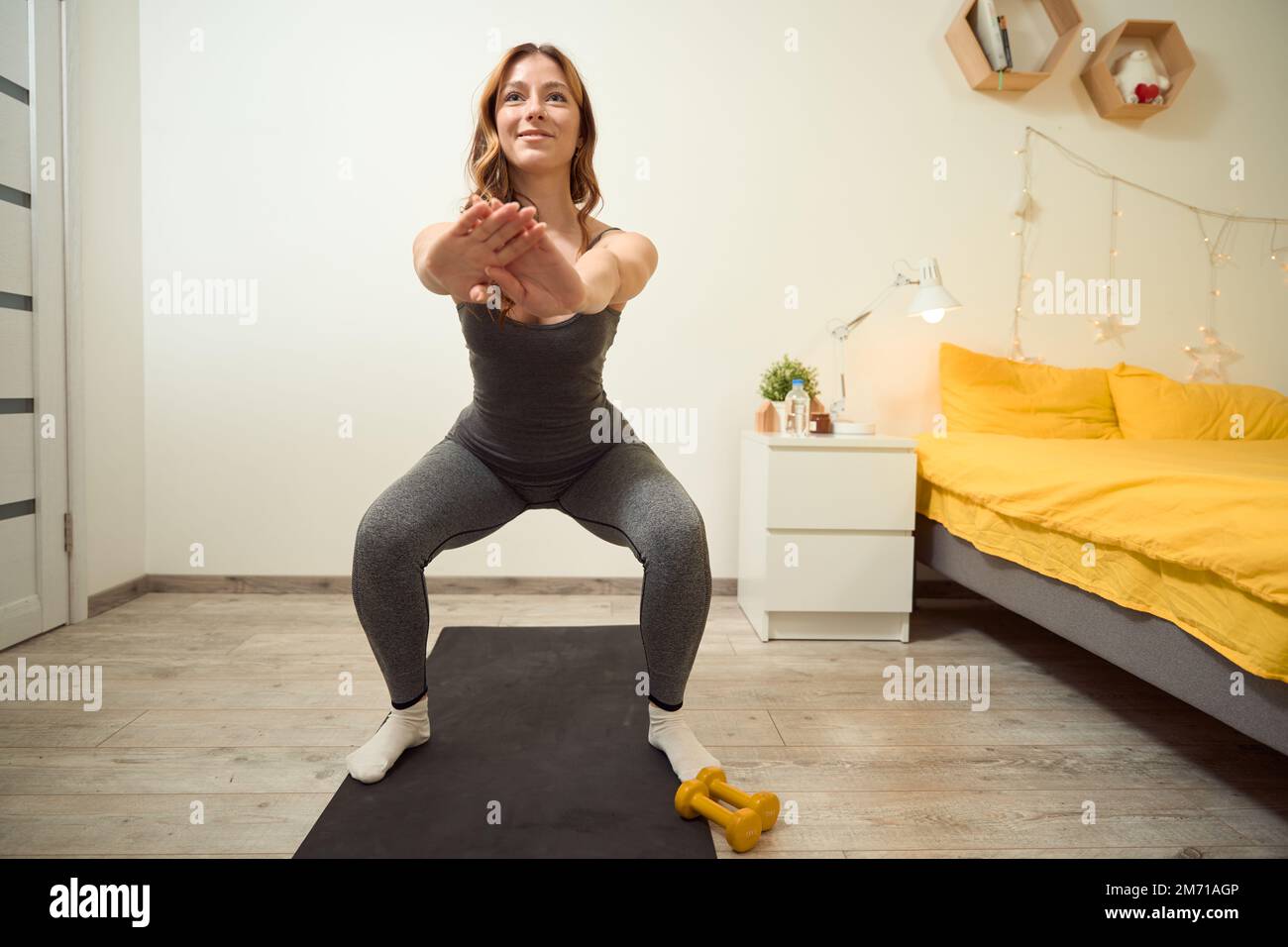 Joyous fit female performing lower-body exercise at home Stock Photo ...