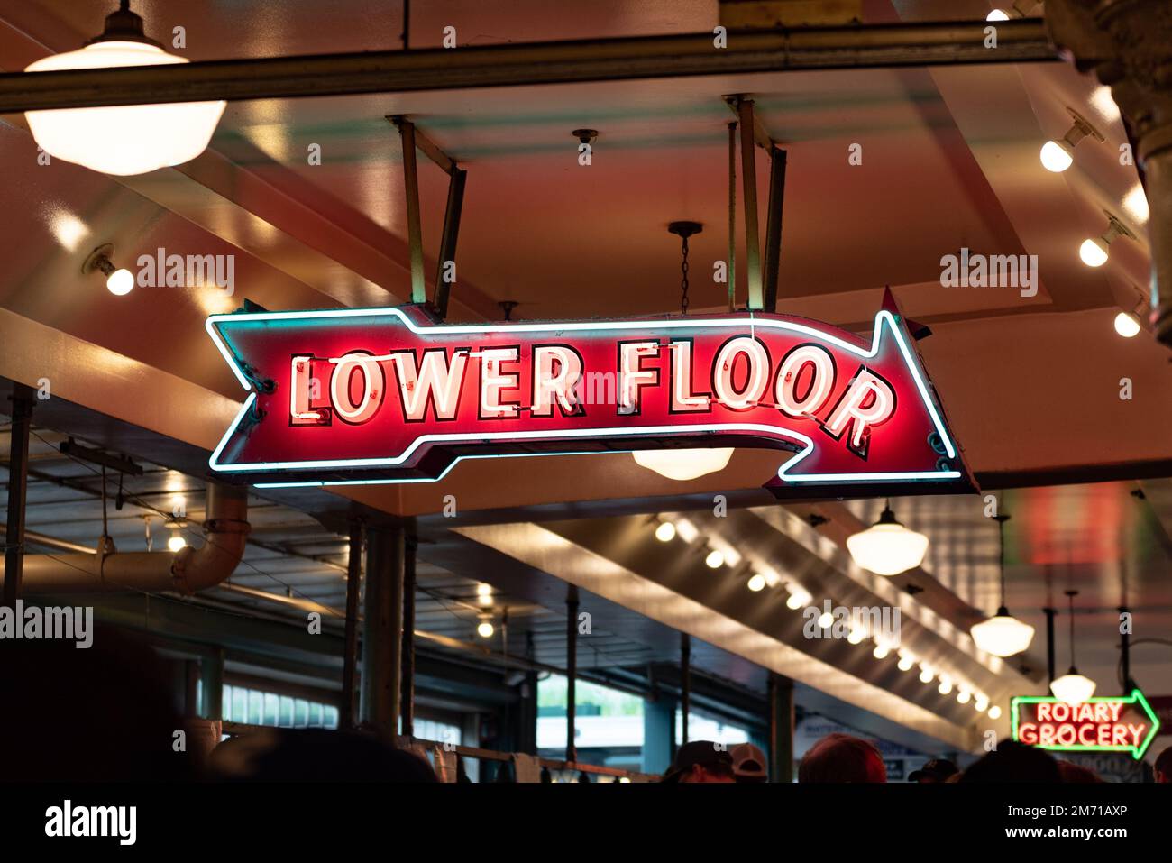 An illuminated arrow sign with lower floor text hanging on the ceiling ...