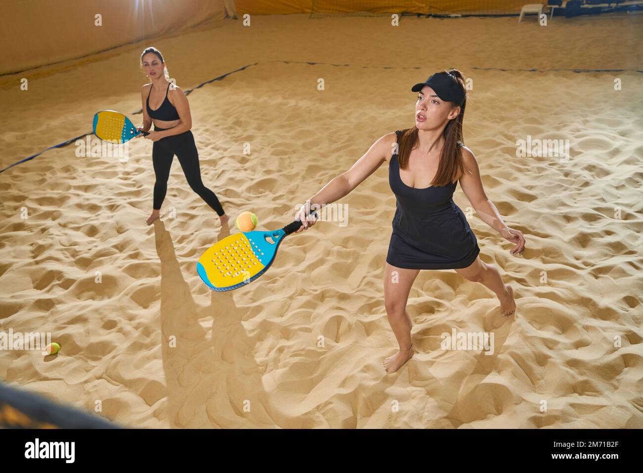 Two women taking tennis ball pass during an indoor game Stock Photo - Alamy