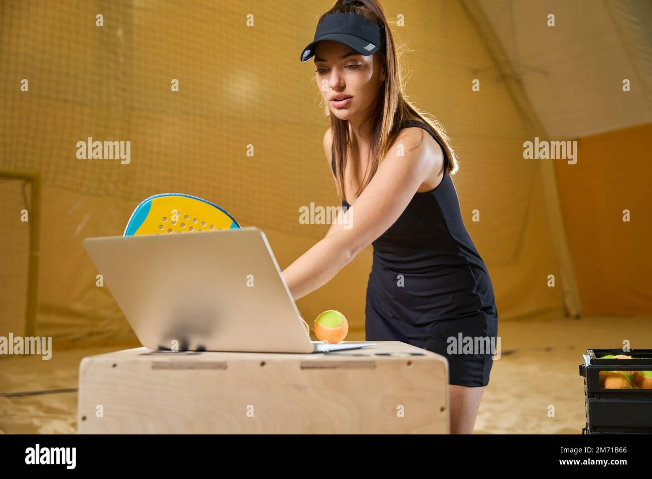 Woman holds hand near computer monitor on table with tennis ball Stock ...