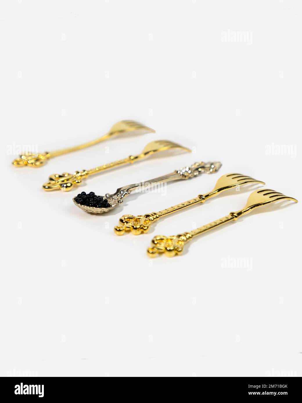 Composition of golden dessert spoon with black sturgeon caviars and ...