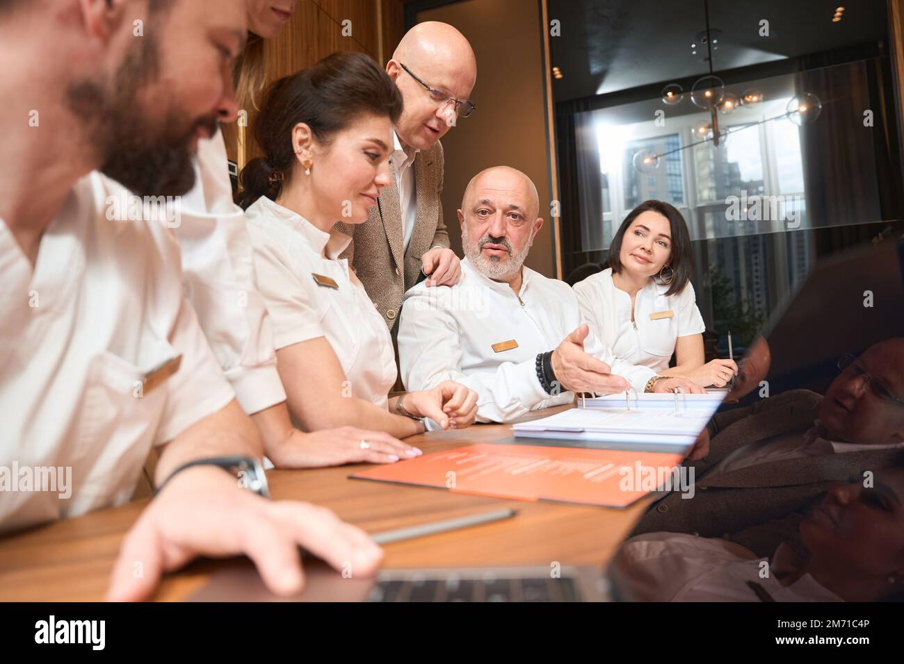 Elderly clinic manager is sitting surrounded by team of employees Stock ...