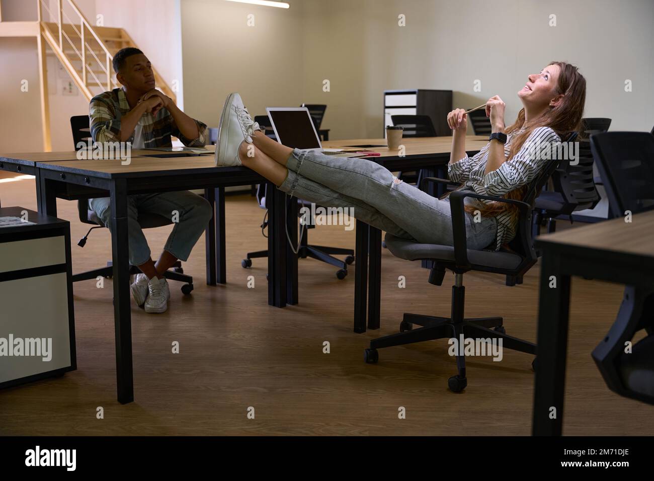 Young lady throwing her legs on the table while talking with her ...