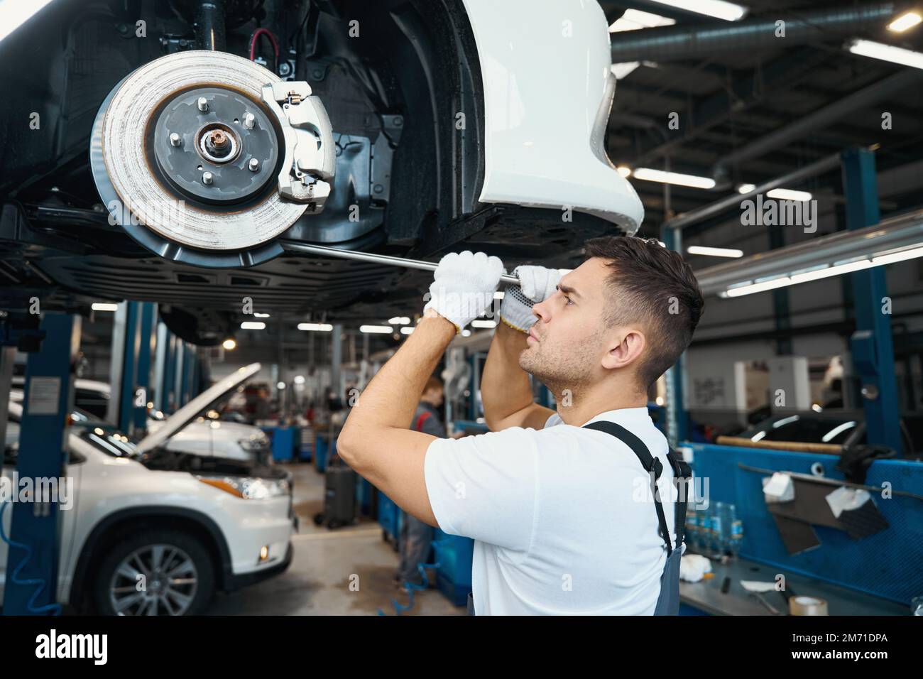 Mechanic removing old wheel from car in tire fitting Stock Photo - Alamy