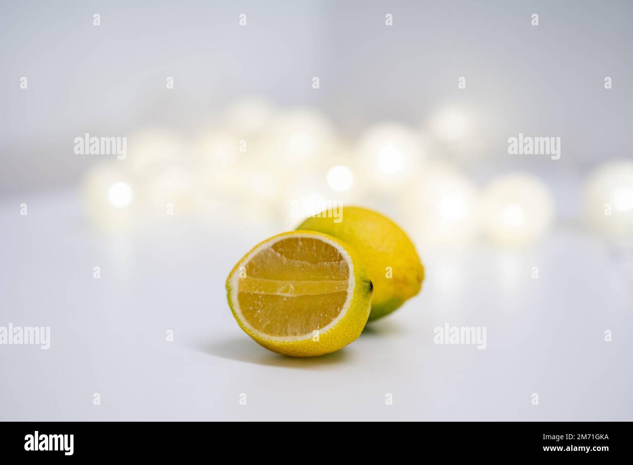 Half a lemon is placed on top of a whole lemon. White background with ...