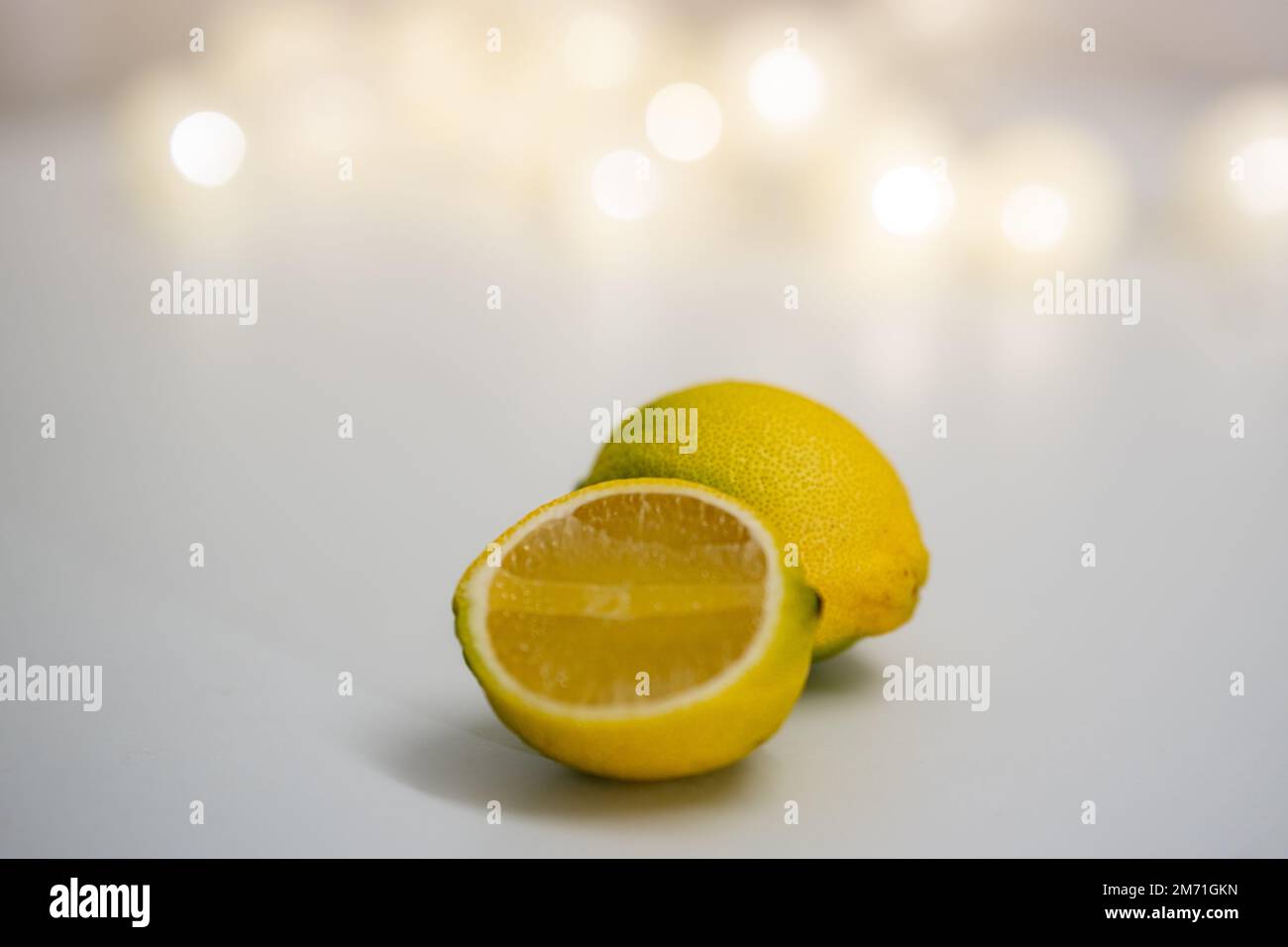 Half a lemon is placed on top of a whole lemon. White background with ...
