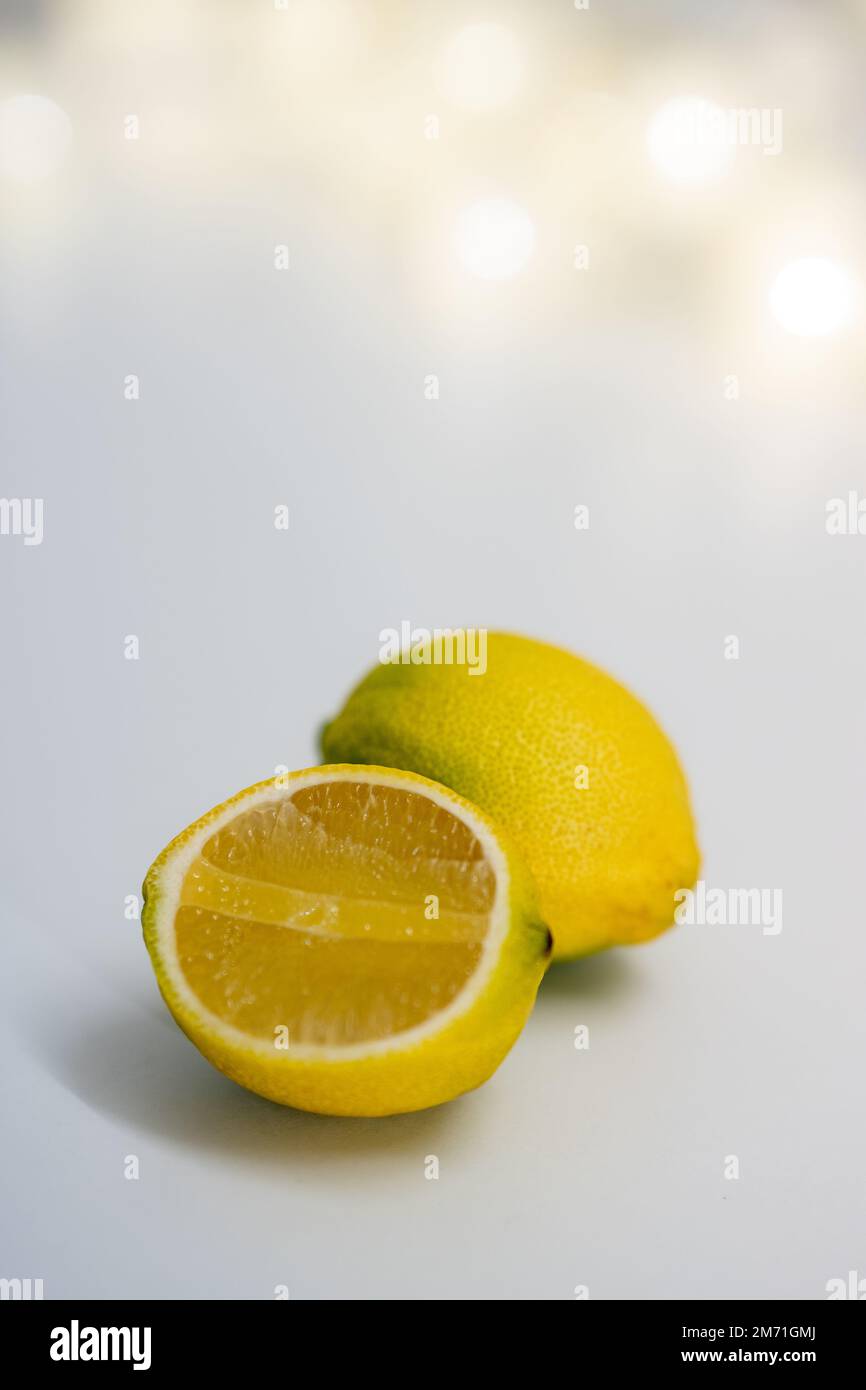 Half a lemon is placed on top of a whole lemon. White background with ...