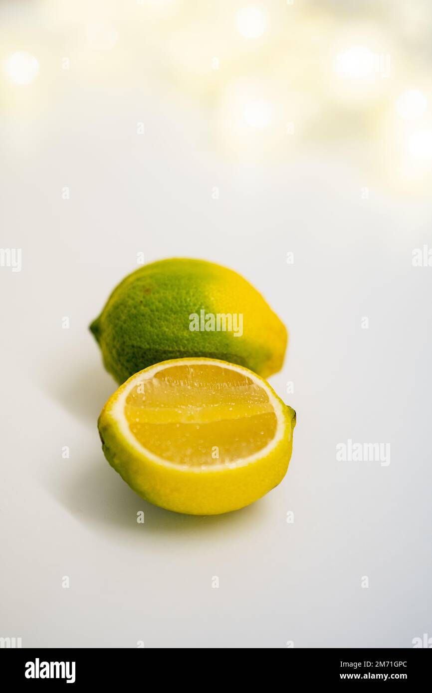 Half a lemon is placed on top of a whole lemon. White background with ...