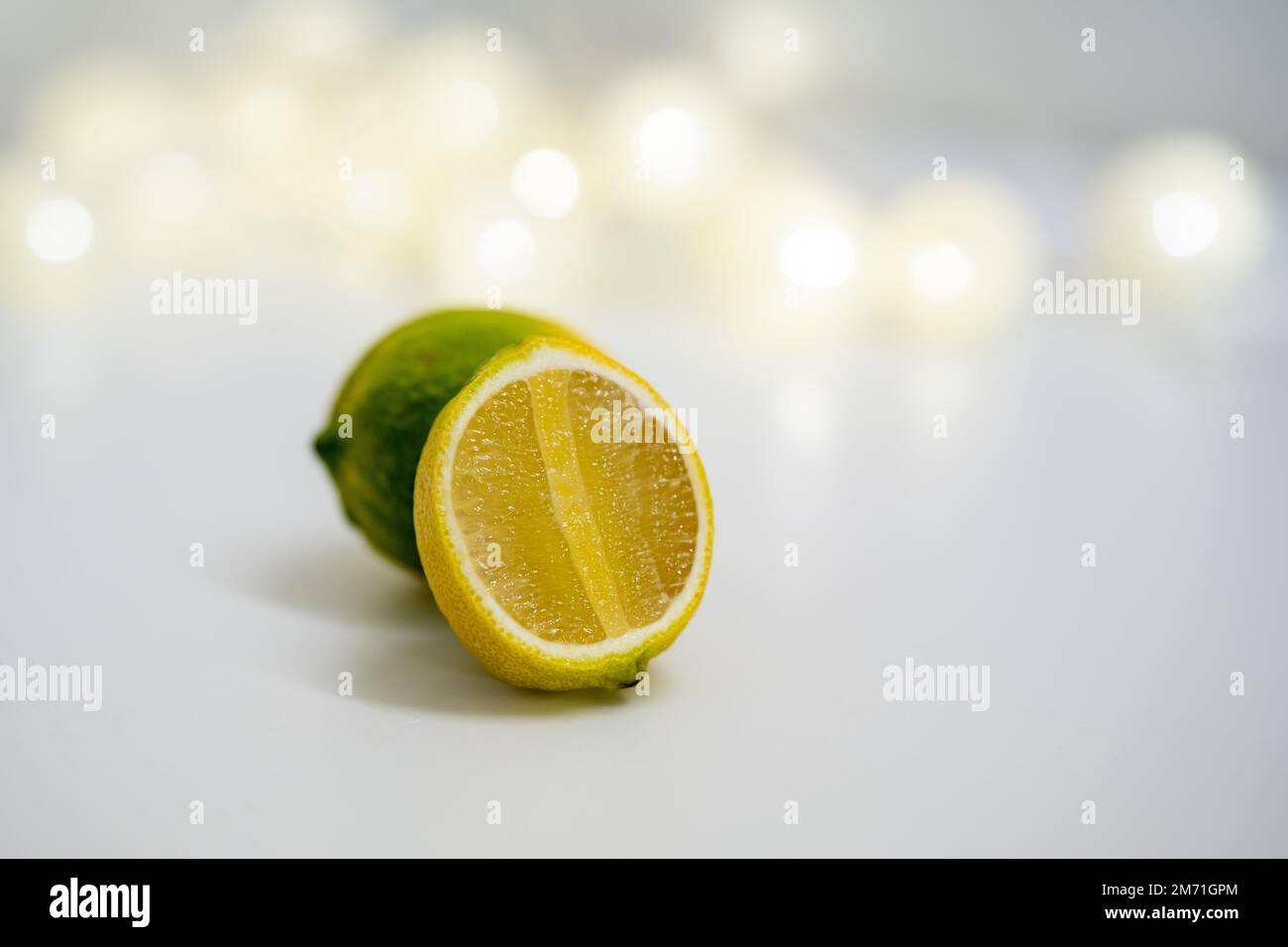 Half a lemon is placed on top of a whole lemon. White background with ...