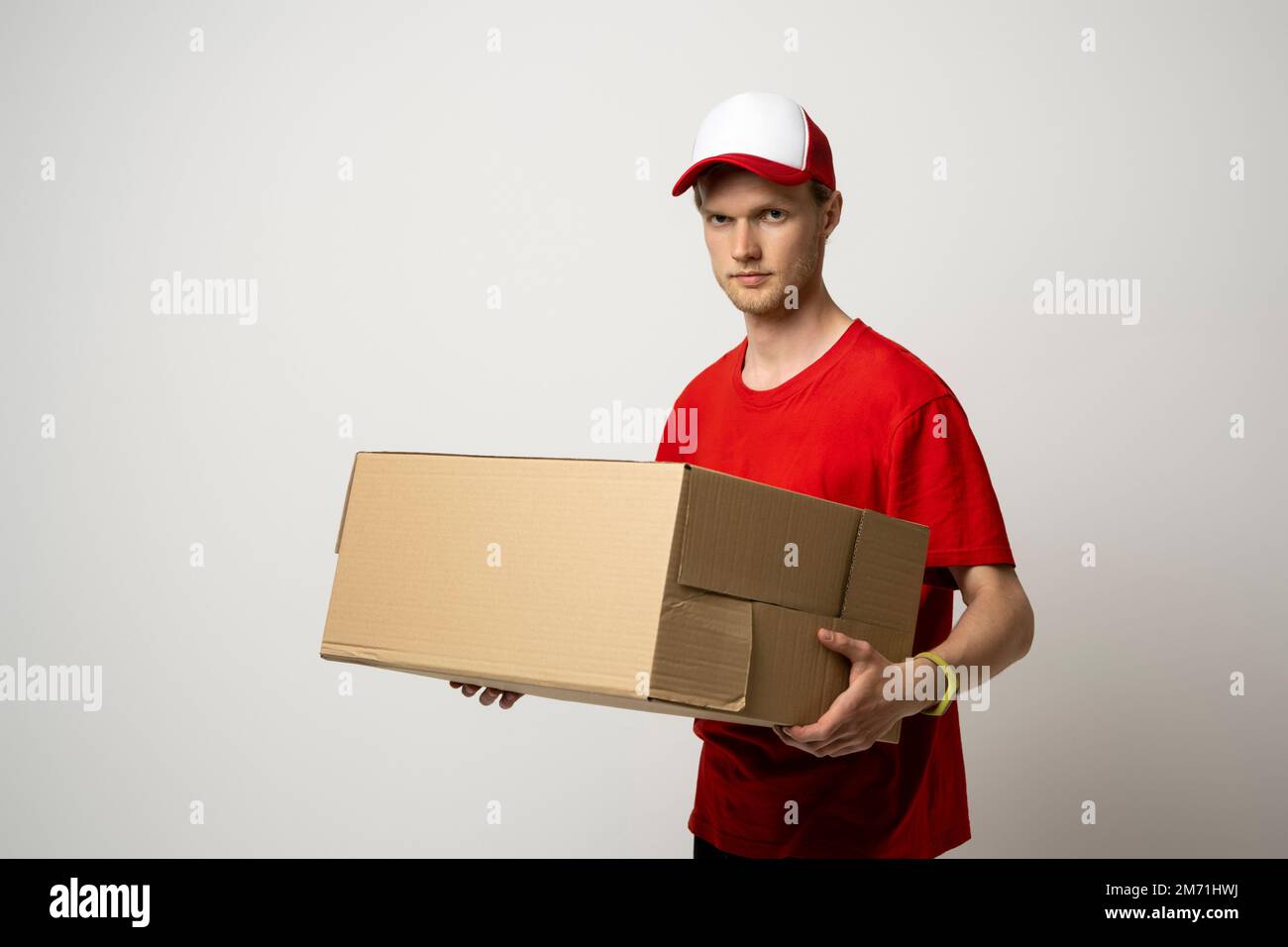 Courier man in red uniform carrying a box, parcel on white background ...
