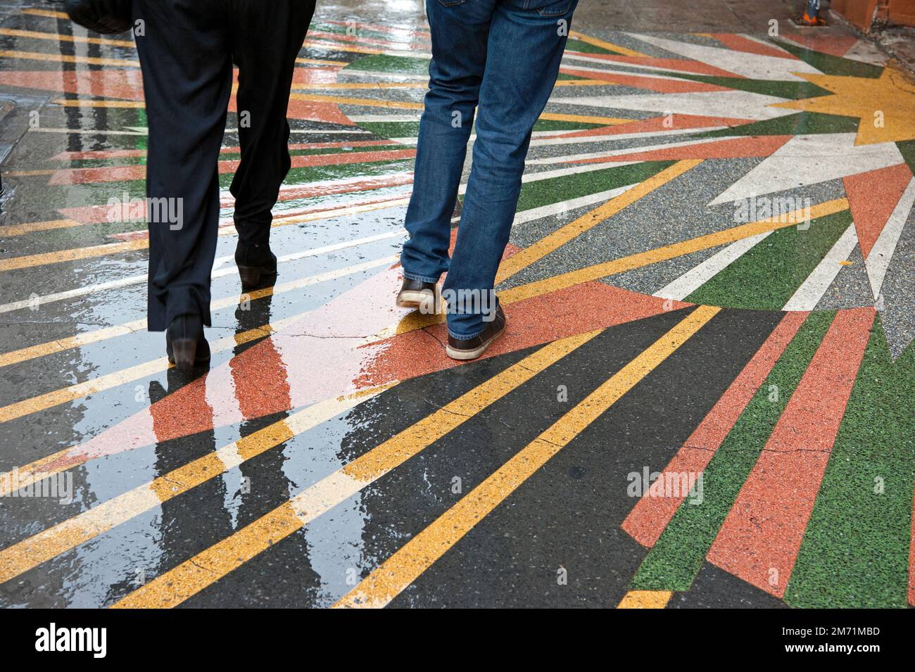 People walking over an old detail of sidewalk outside a movie theater ...