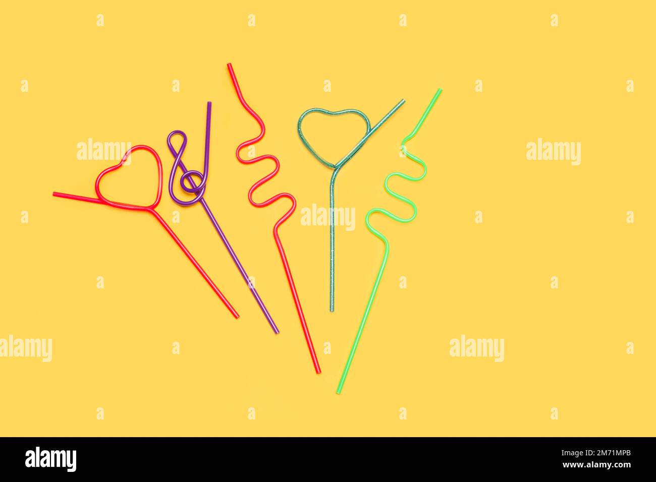 Heart, treble clef and zig zag shape colored drinking straws on a ...