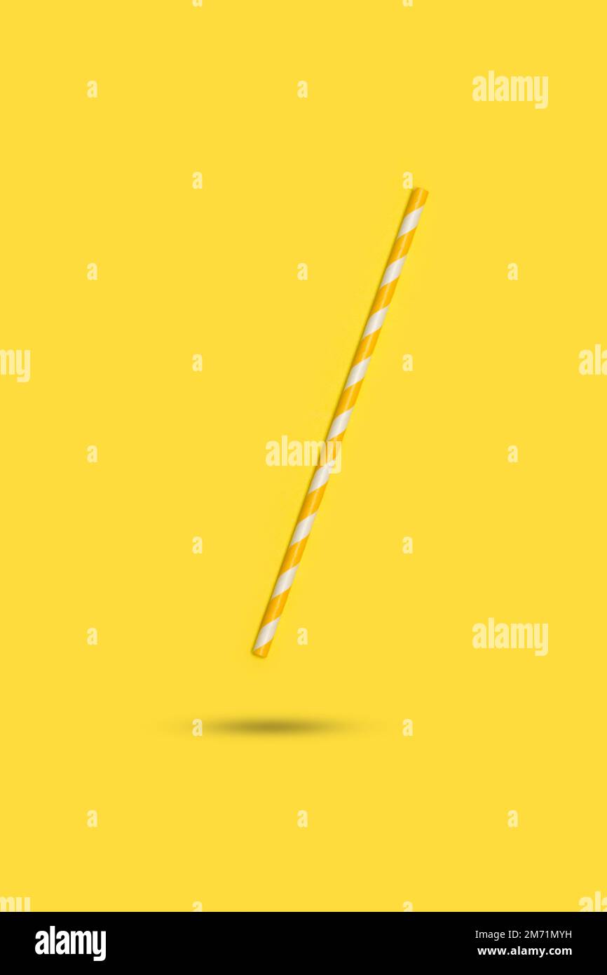 White and yellow striped drinking straw floating on a yellow background ...