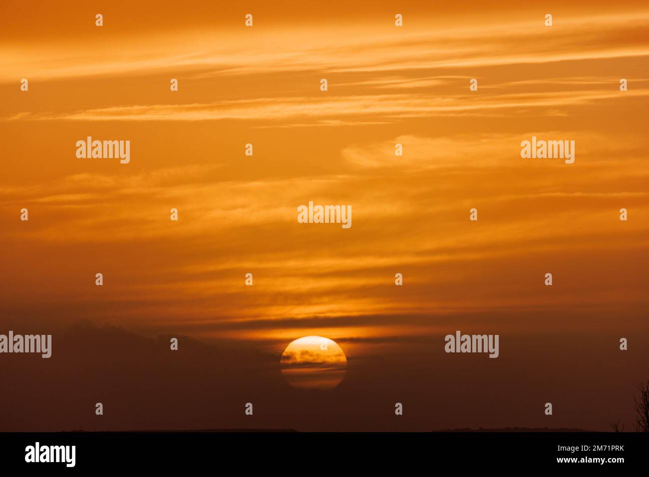 The setting sun disappearing behind some cloud cover Stock Photo - Alamy