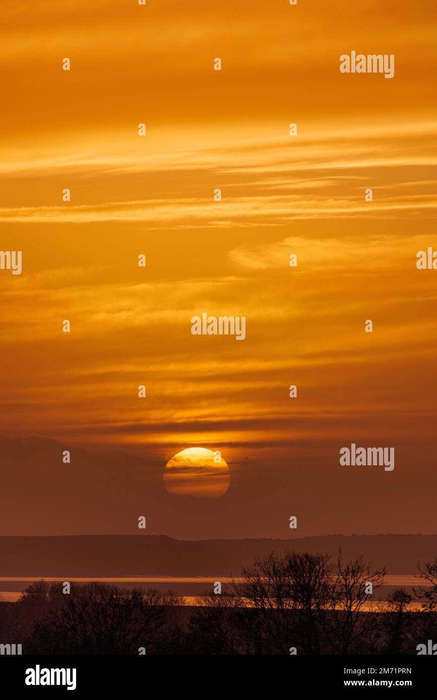 The setting sun disappearing behind some cloud cover Stock Photo - Alamy