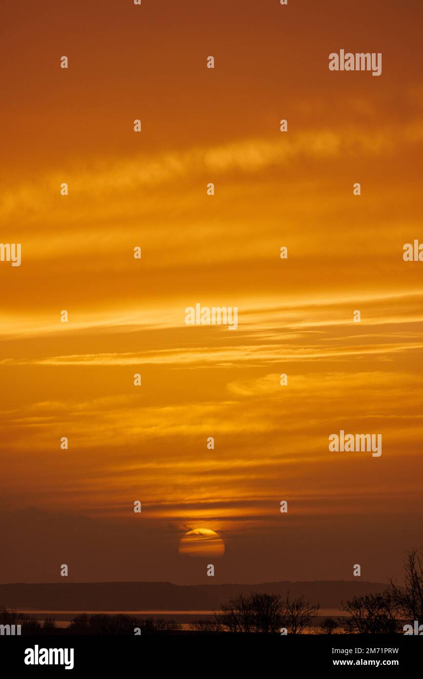The setting sun disappearing behind some cloud cover Stock Photo - Alamy