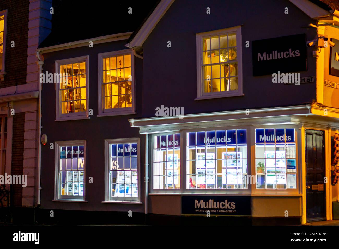 Illuminated estate agents shop window with residential apartment above ...