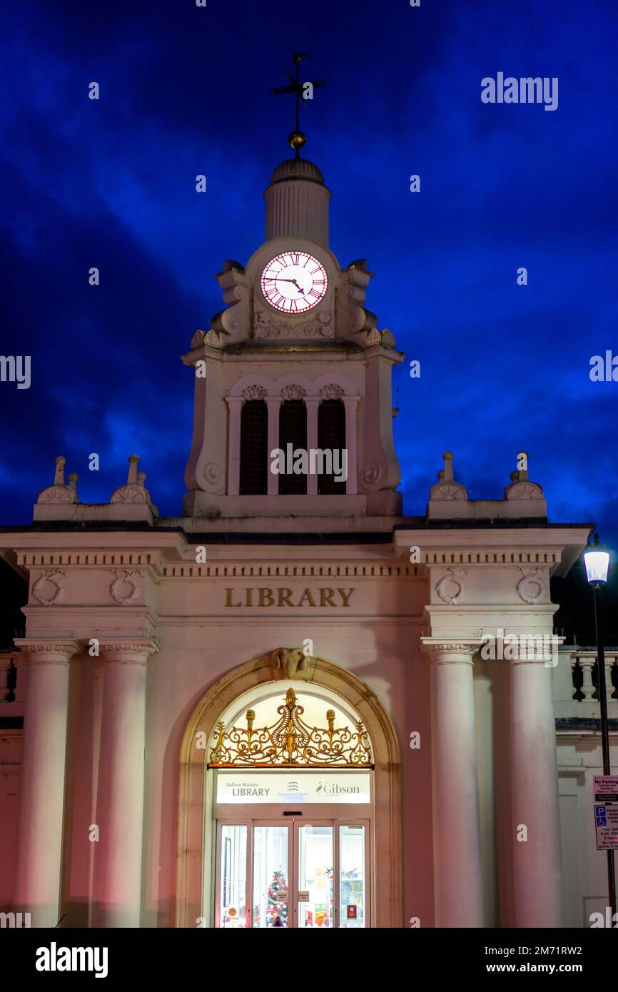 Ornate illuminated clock tower above a public library at dusk in ...