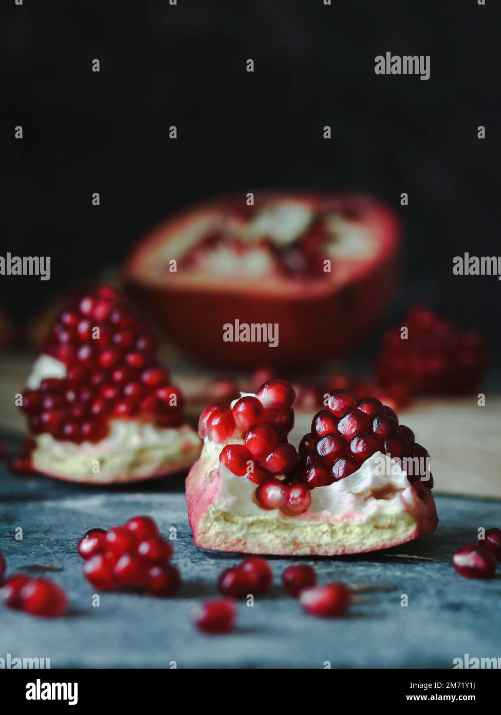 Open pomegranate on a cutting board over a gray dark gray background ...