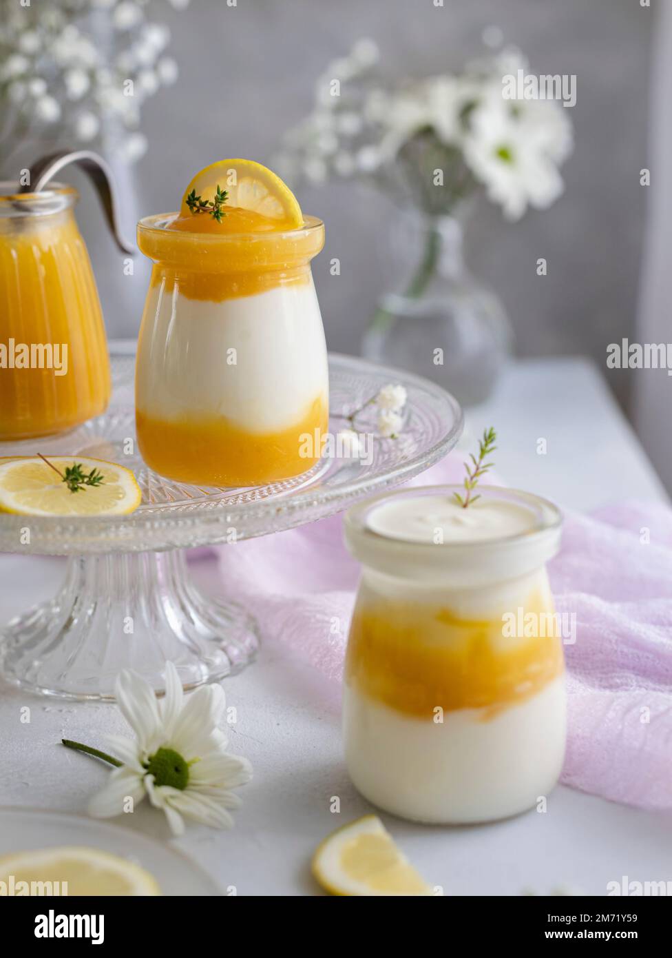 Lemon curd and greek yogurt with thyme in glass jars. Soft romantic ...