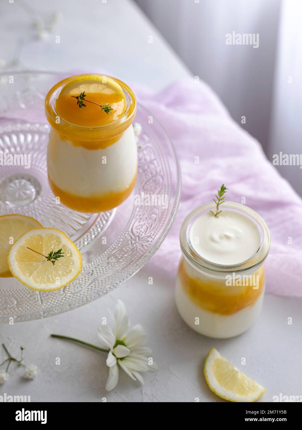 Lemon curd and greek yogurt with thyme in glass jars. Soft romantic ...