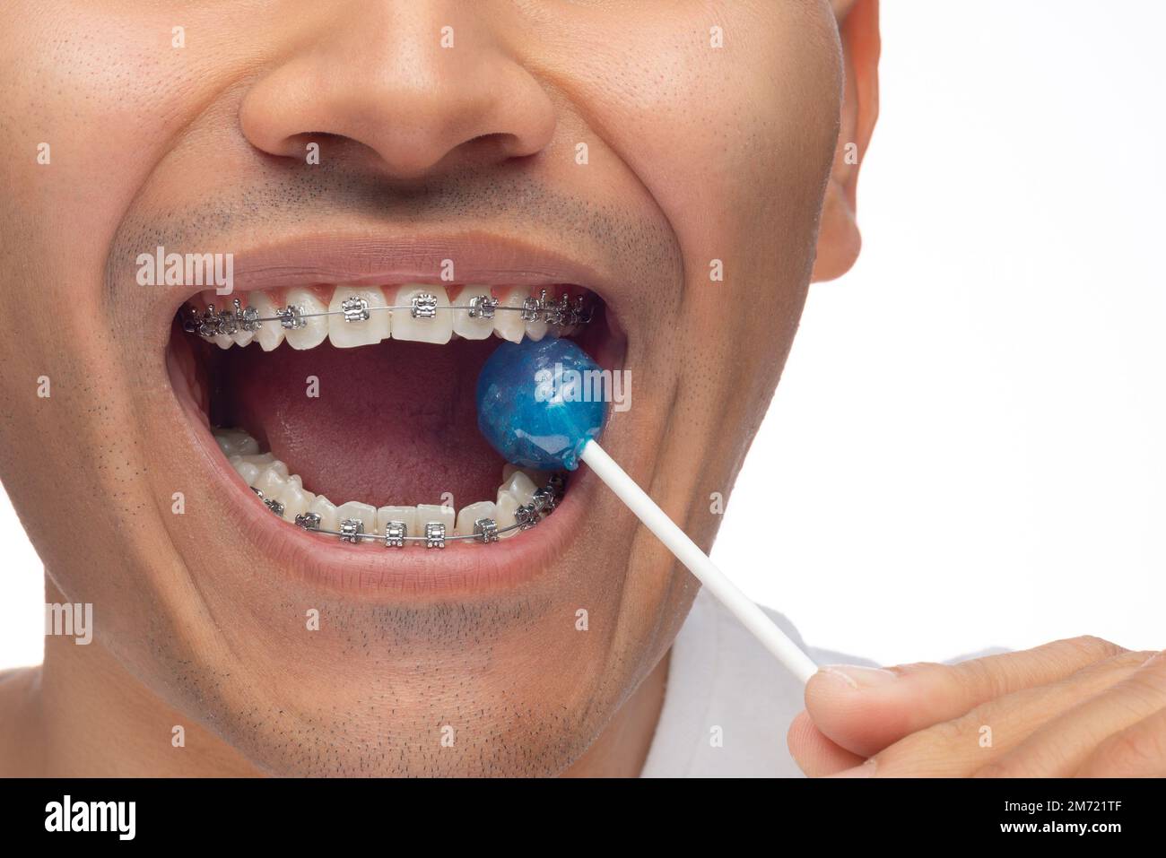 Hispanic man with brown skin, bites a palette of sweet blue color with ...