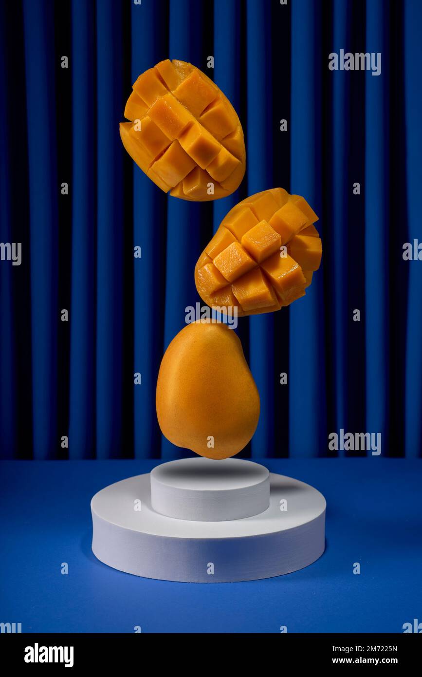 fresh sliced mango for cocktail, flying fruit minimal style on blue ...