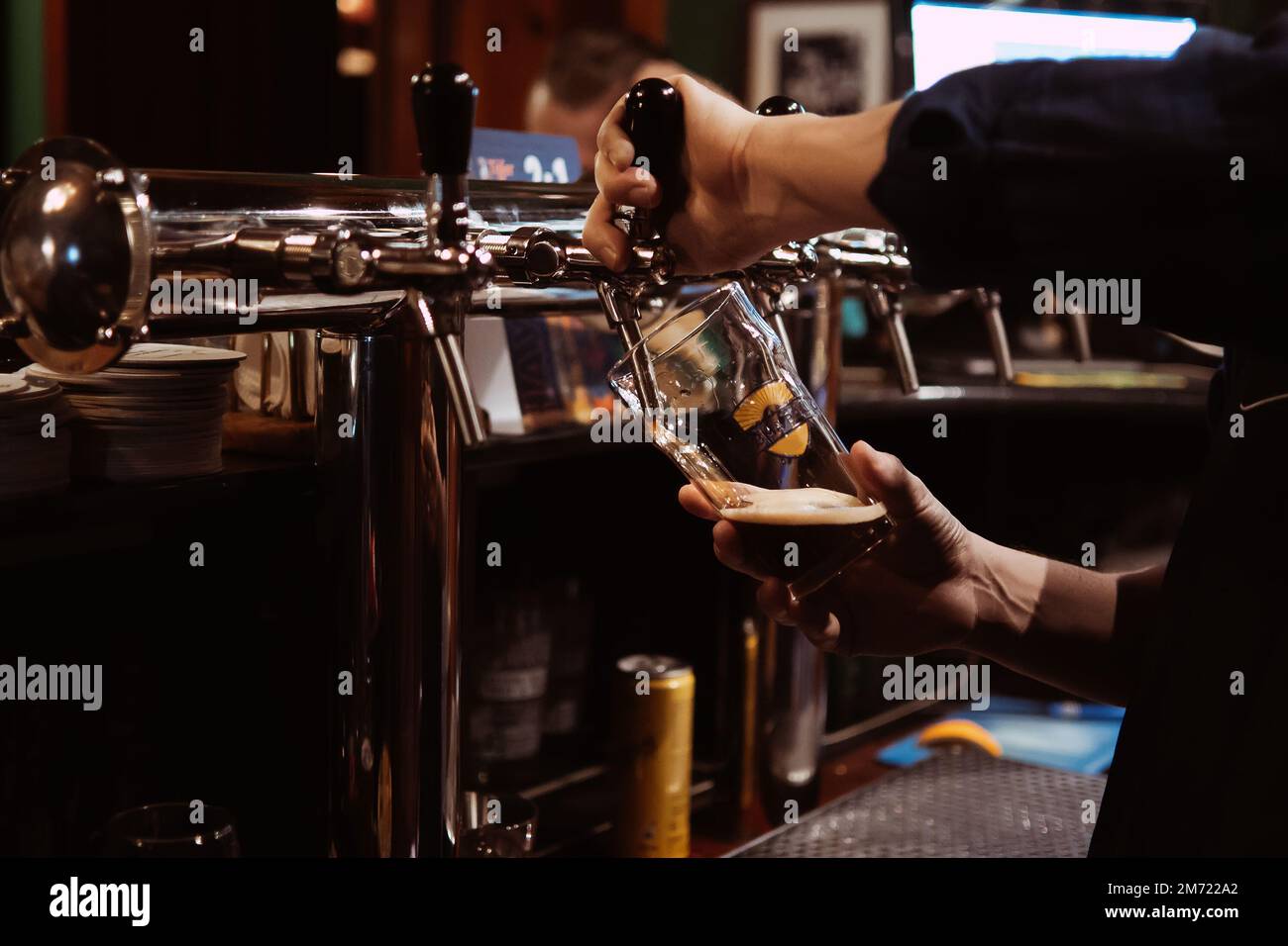 bartender pours dark beer from tap in the pub behind the bar Stock ...