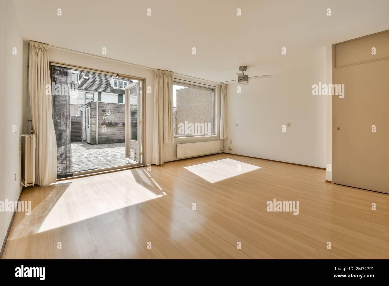 an empty living room with wood flooring and sliding glass door leading ...